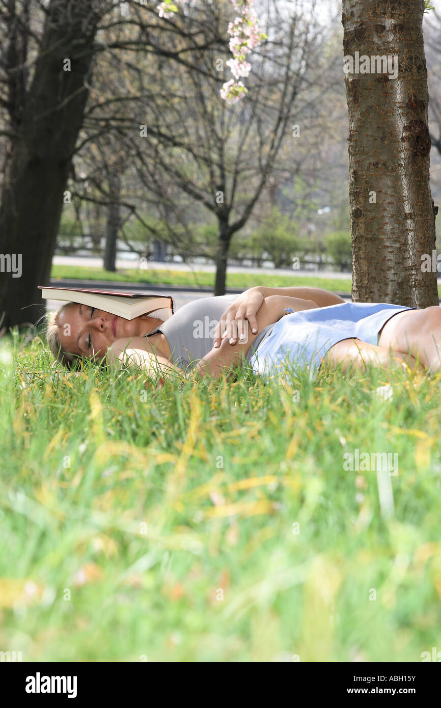young woman reading a book under a tree Stock Photo - Alamy