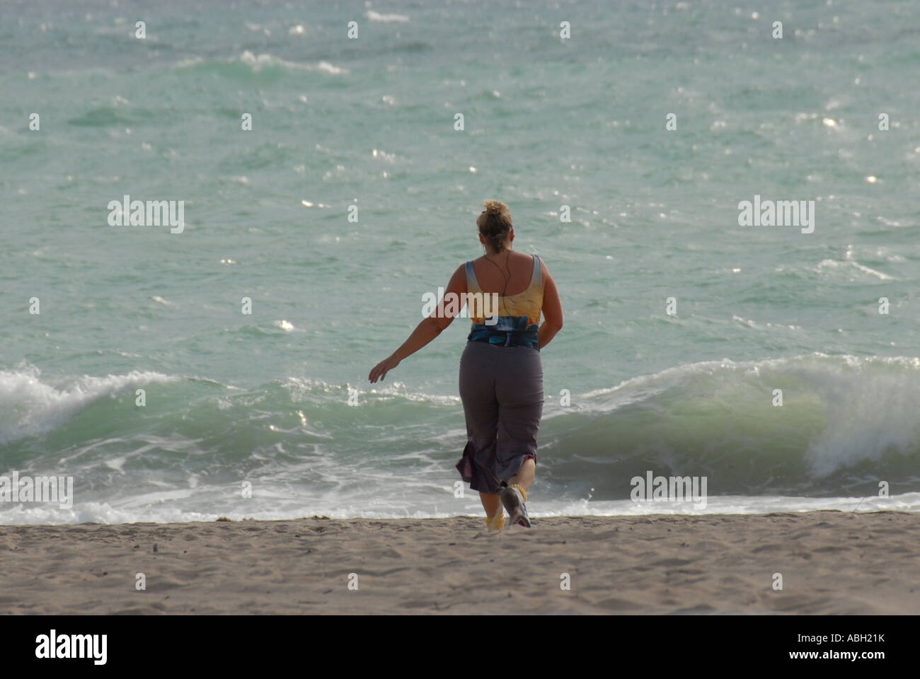 Young woman walking toward surf Stock Photo - Alamy