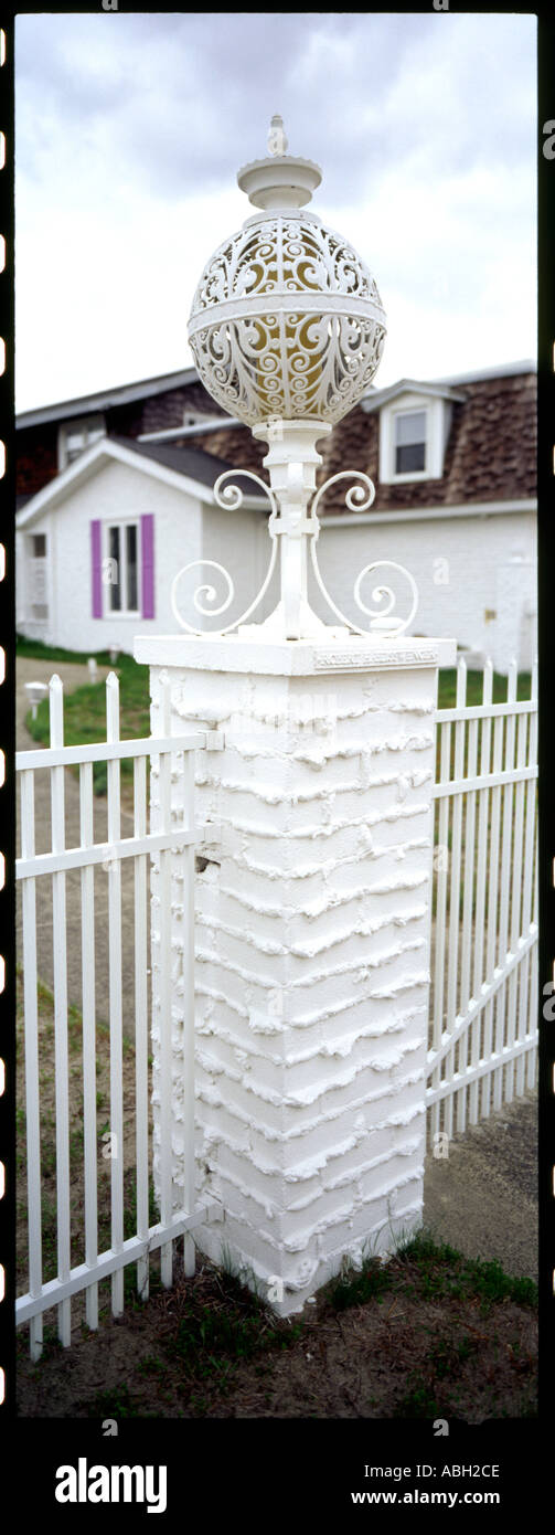 a white brick fence post topped by an ornate globe wrought iron lamp in ...