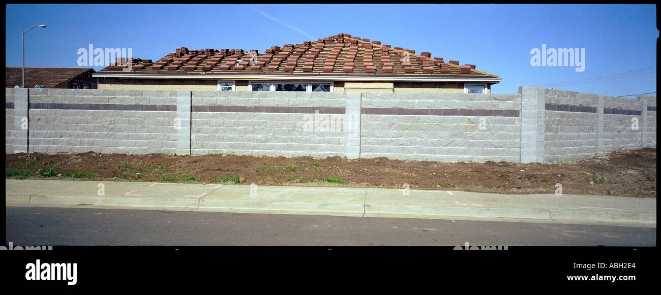 a street in a new suburban neighborhood with a sound wall in front of a ...
