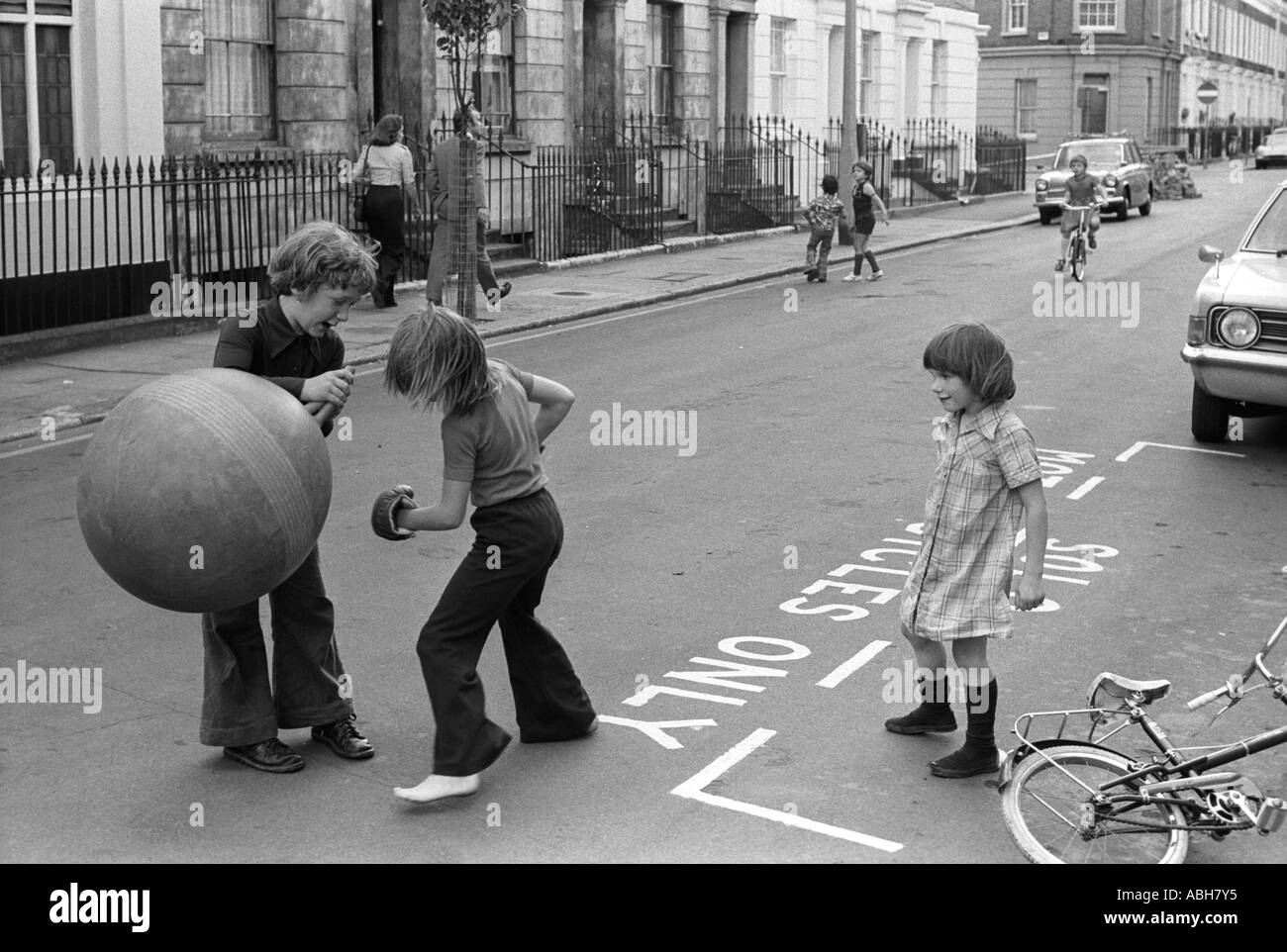 Young children playing safely in street bare feet riding their bikes ...