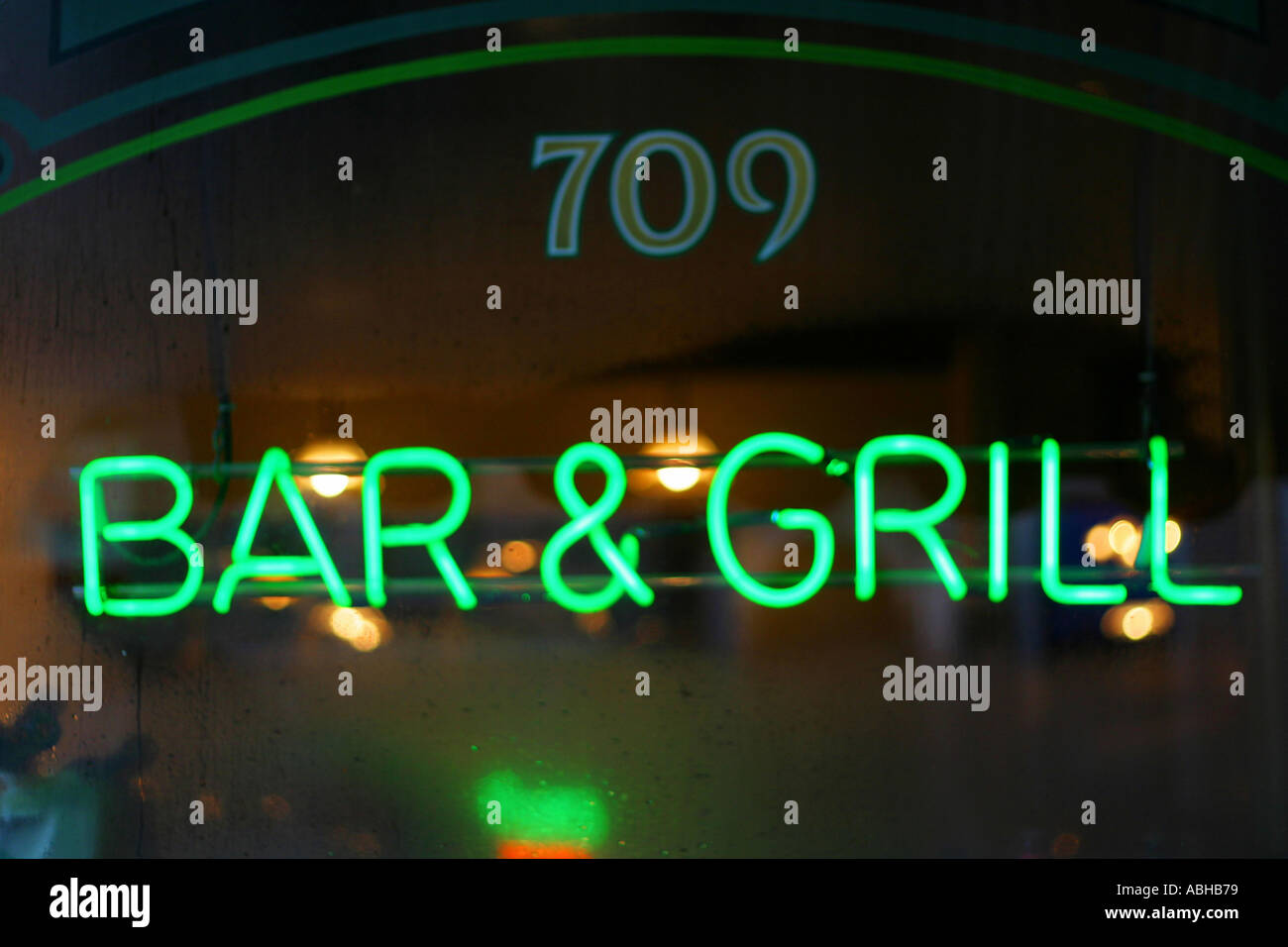 noen sign saying BAR GRILL green lettering night time rain streaked ...