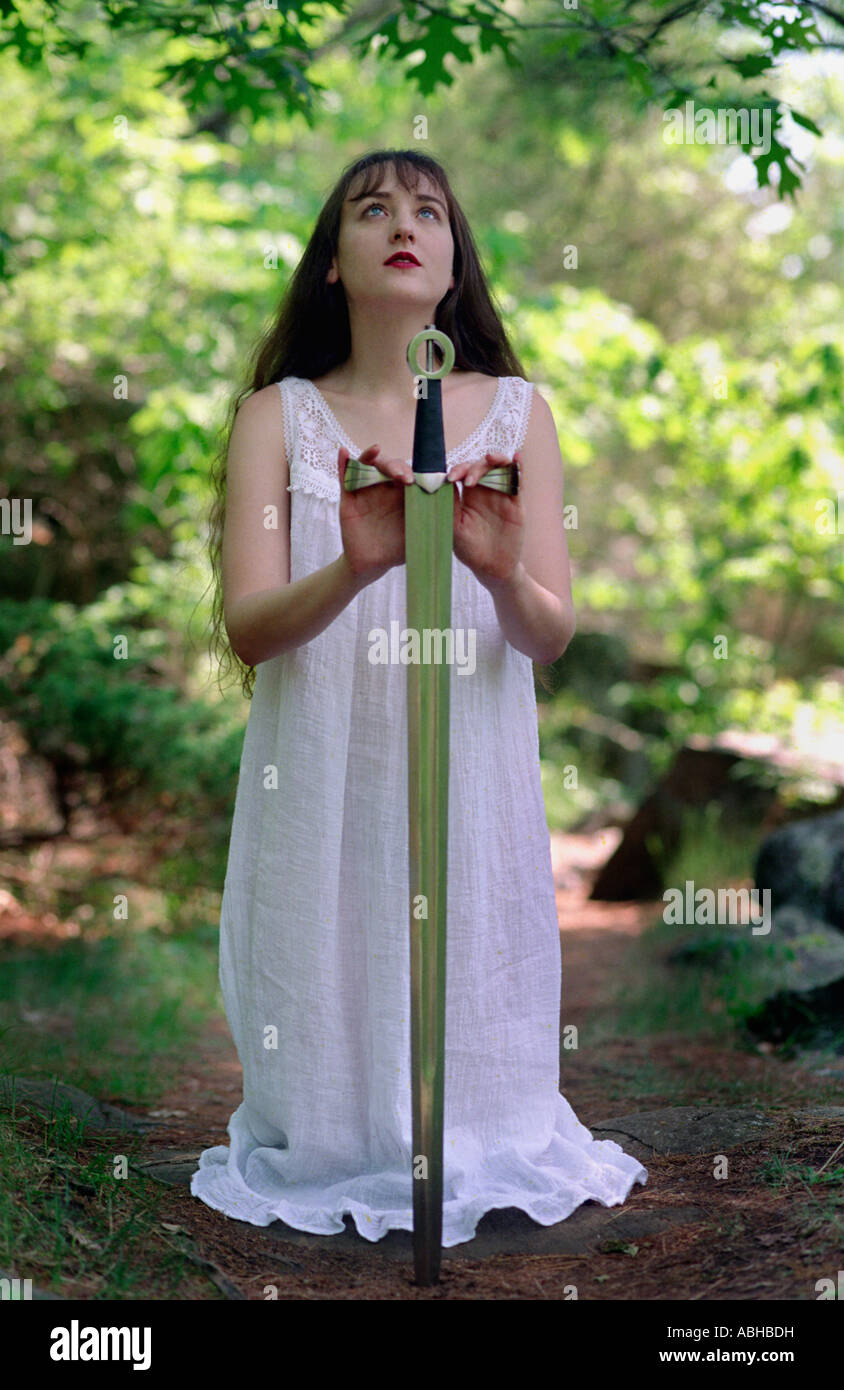 A young woman kneeling while meditating with a sword Stock Photo - Alamy
