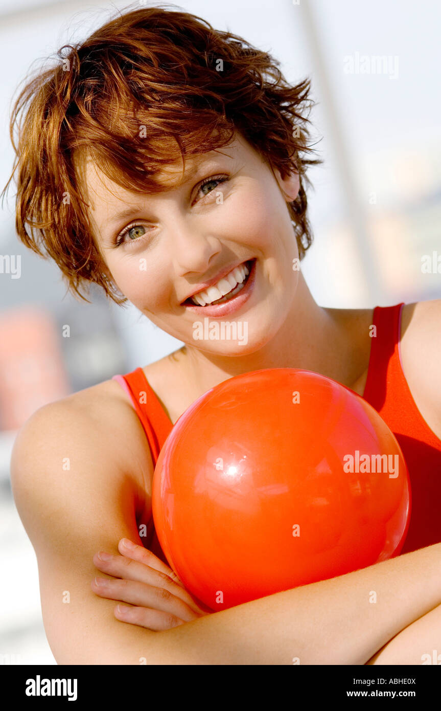 Portrait of a young woman with red ball, smiling for camera Stock Photo ...