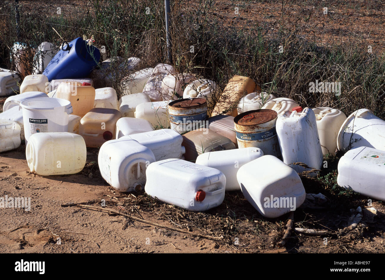 Discarded pesticide cartons cans beside fence of orange orchard in ...
