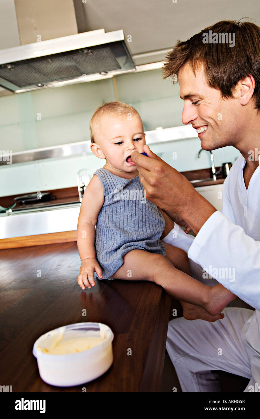 Father and son in kitchen, man feeding his baby, indoors Stock Photo ...