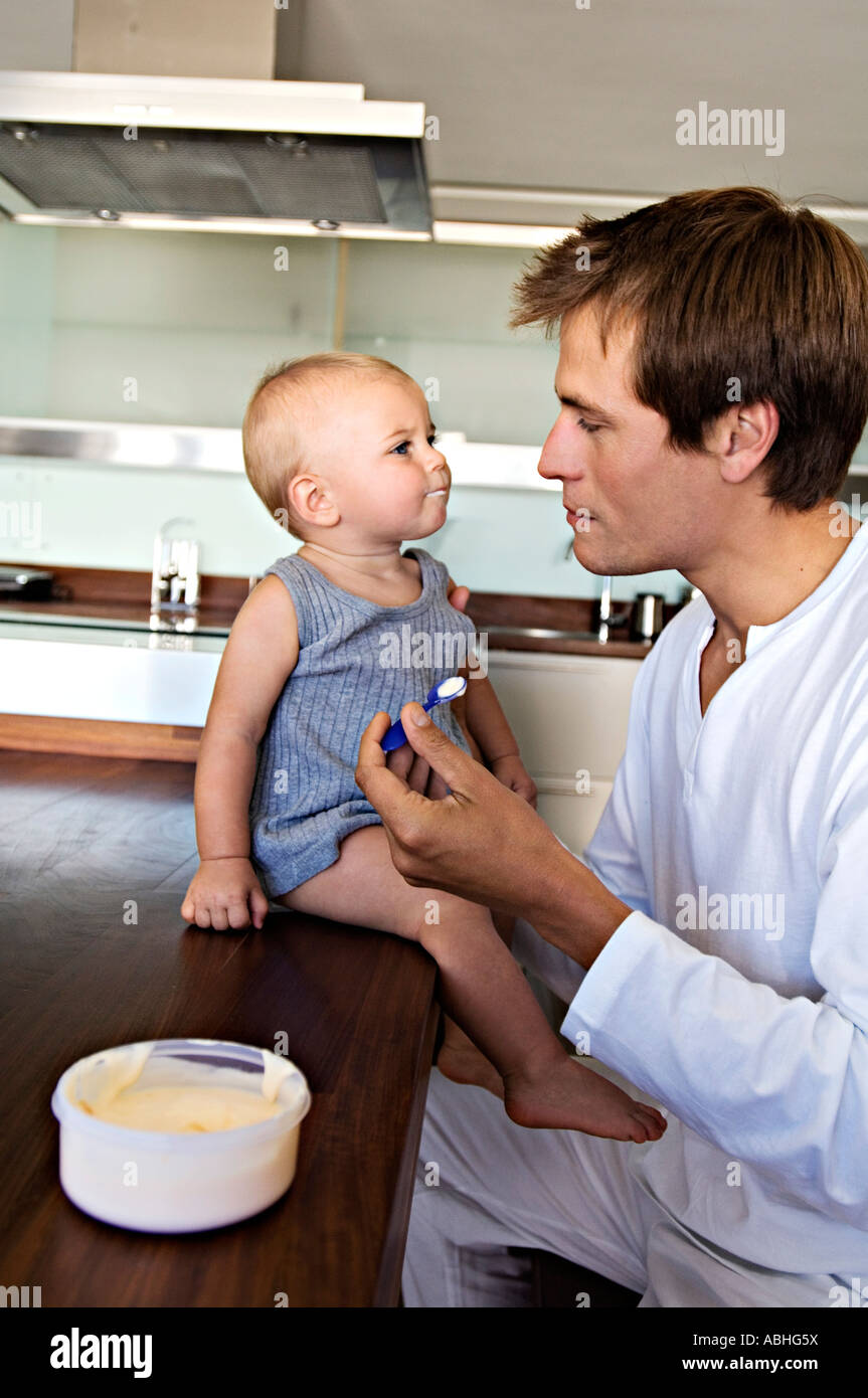Father and son in kitchen, man feeding his baby, indoors Stock Photo ...