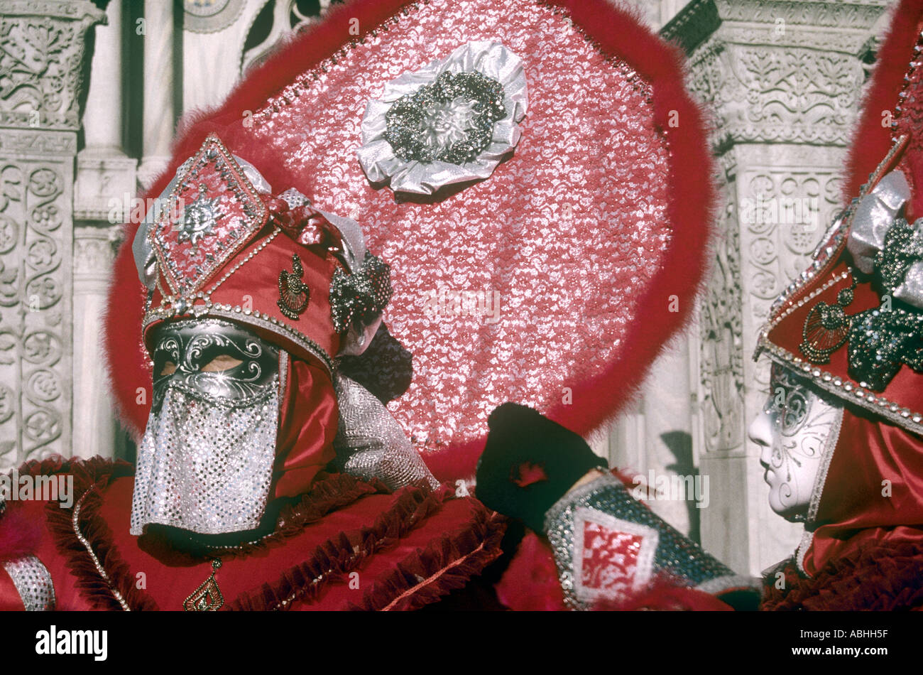 One red clad carnival goer in mask and outfit outside church in Venice ...