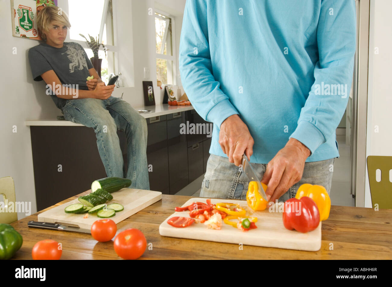 Man cooking, teen sitting in background, indoors Stock Photo - Alamy