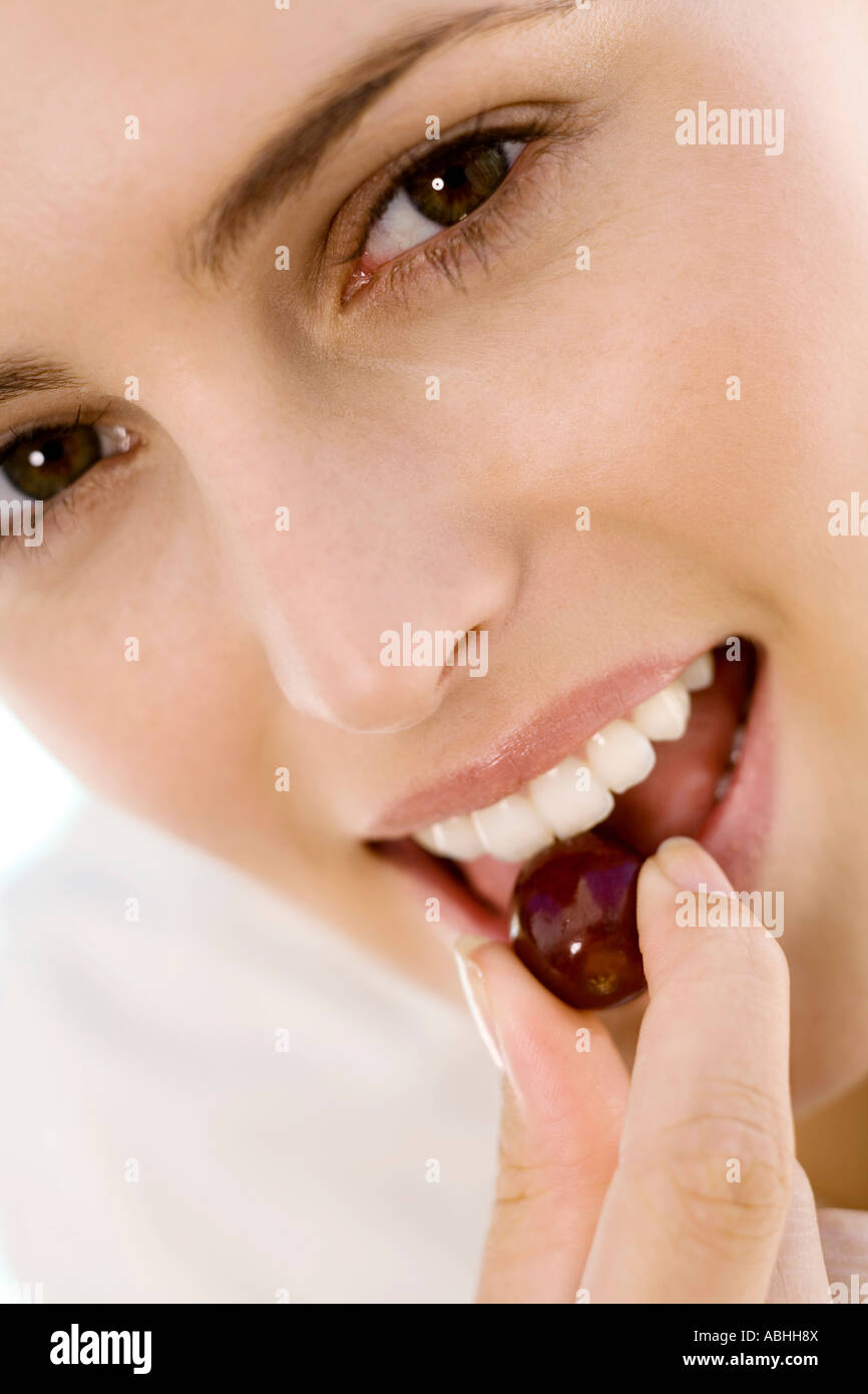 Portrait of a young woman eating a cherry, indoors Stock Photo - Alamy