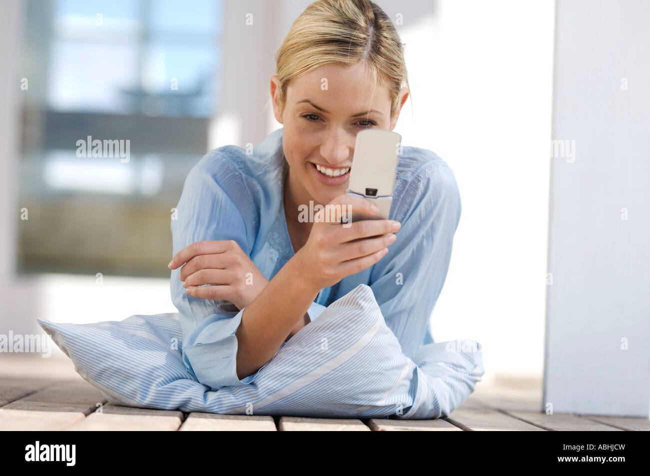Young woman lying on floor, using mobile phone Stock Photo - Alamy