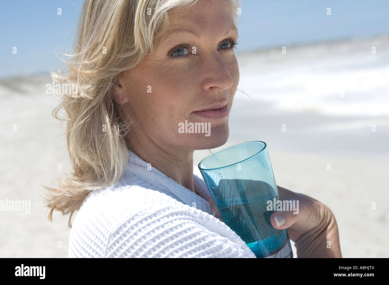 Portrait of thinking woman on the beach, holding glass of water Stock ...