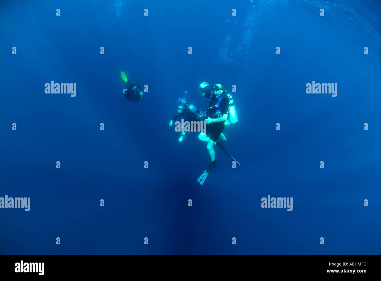Three divers scuba diving in the open water ocean, Raja Ampat Stock ...