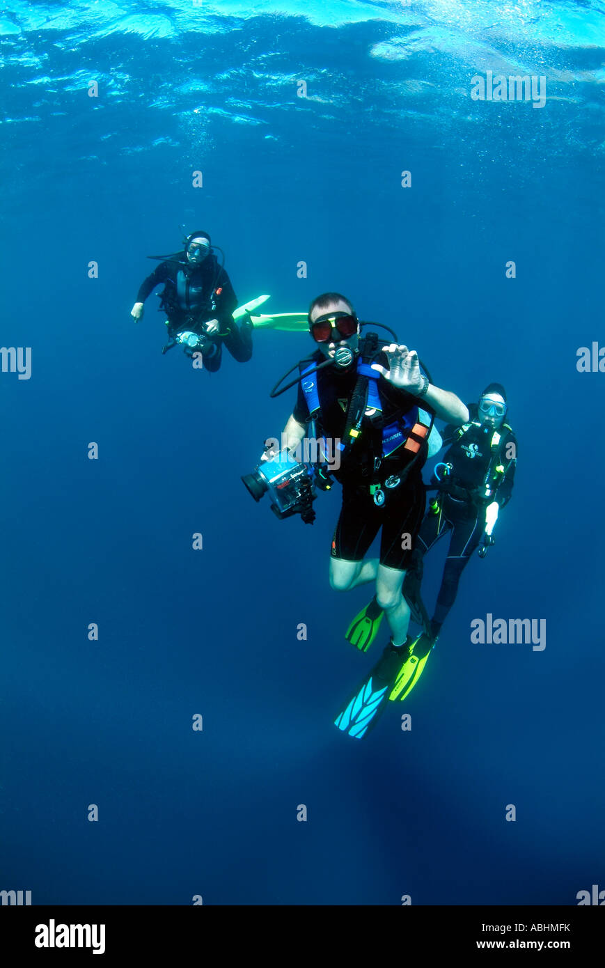 Three divers scuba diving in the open water ocean, Raja Ampat Stock ...