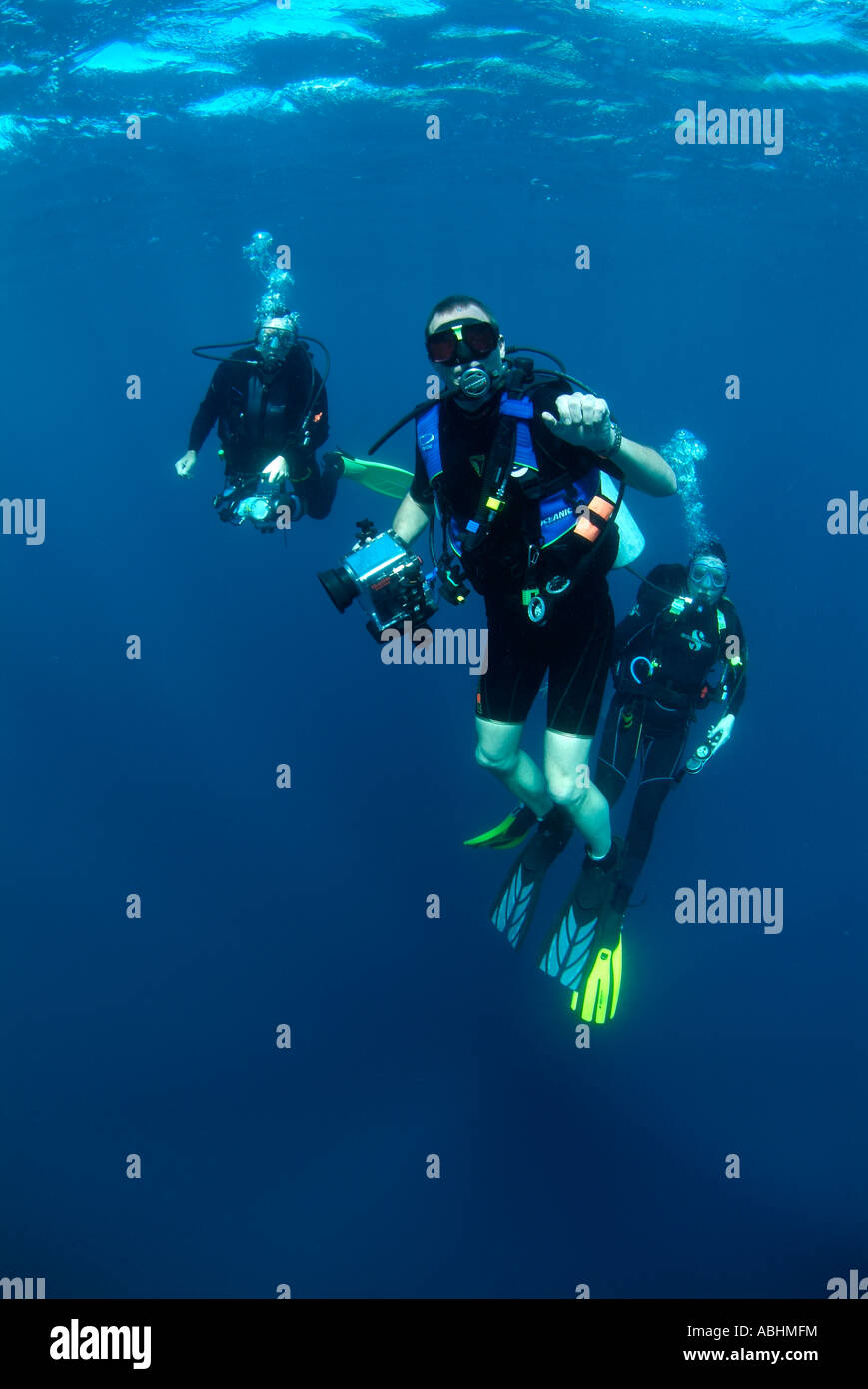 Three divers scuba diving in the open water ocean, Raja Ampat Stock ...