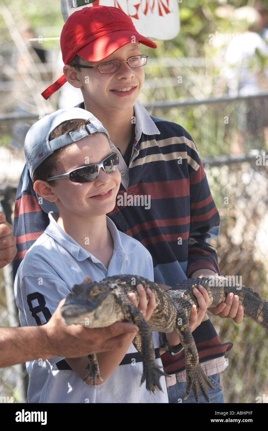 Kids getting proudly photographed with baby alligator in a show after ...