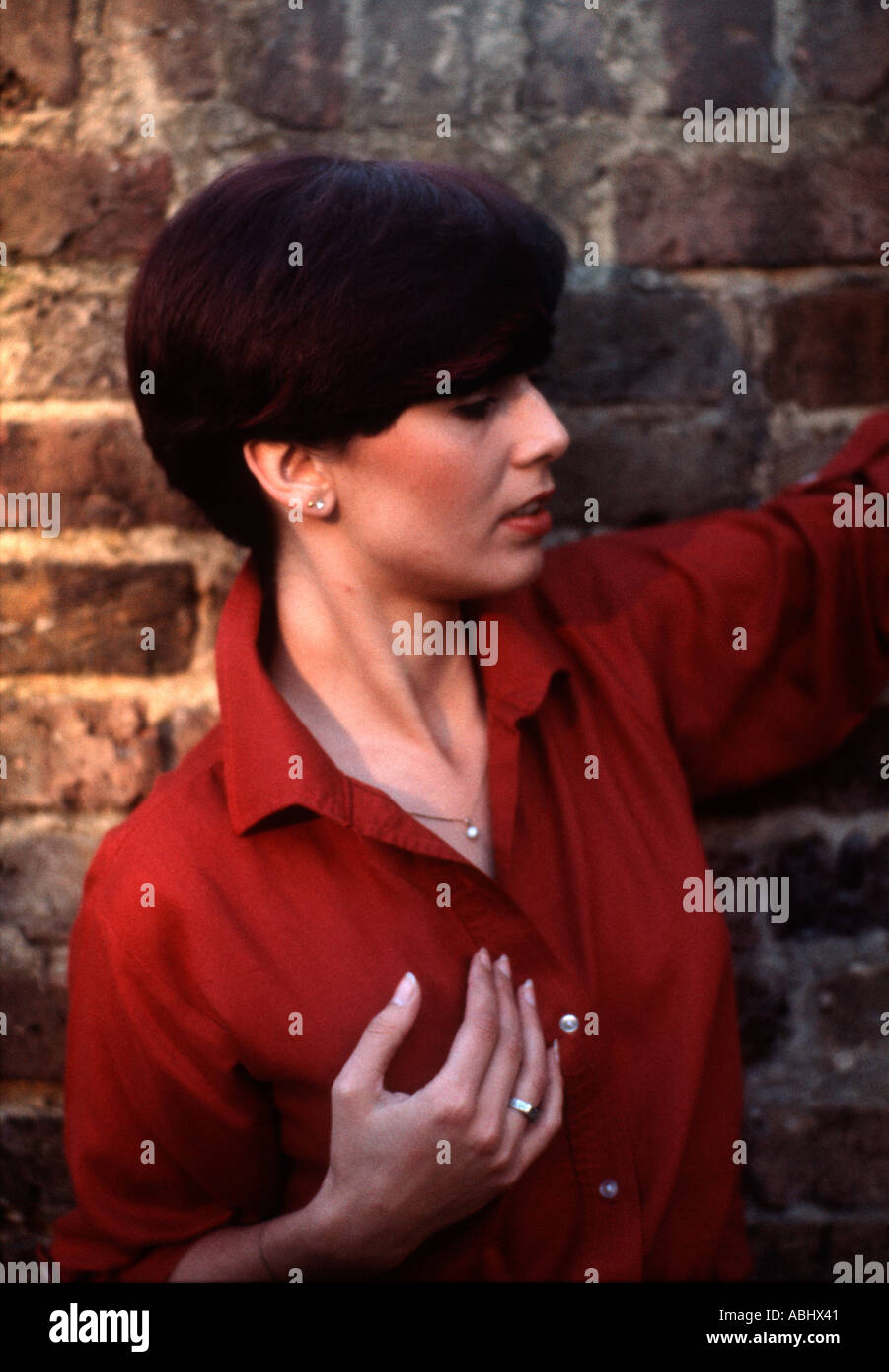 Brunette young woman in a red blouse with a bob haircut side view in ...