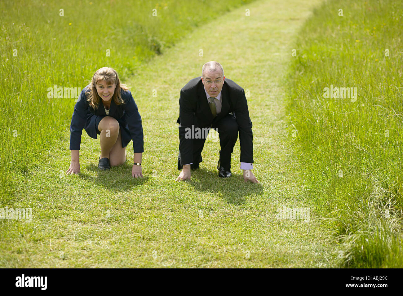 Business man and woman line up to compete in race on grass track Stock ...