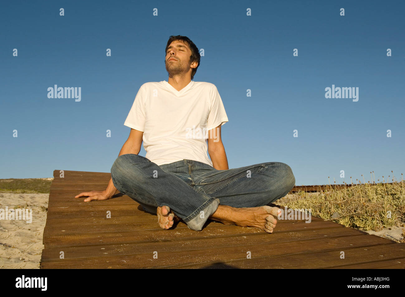Young man sitting cross-legged, outdoors Stock Photo - Alamy