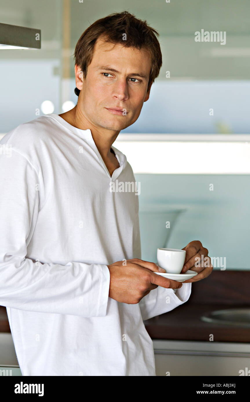 Young thinking man in kitchen, holding coffee cup Stock Photo - Alamy