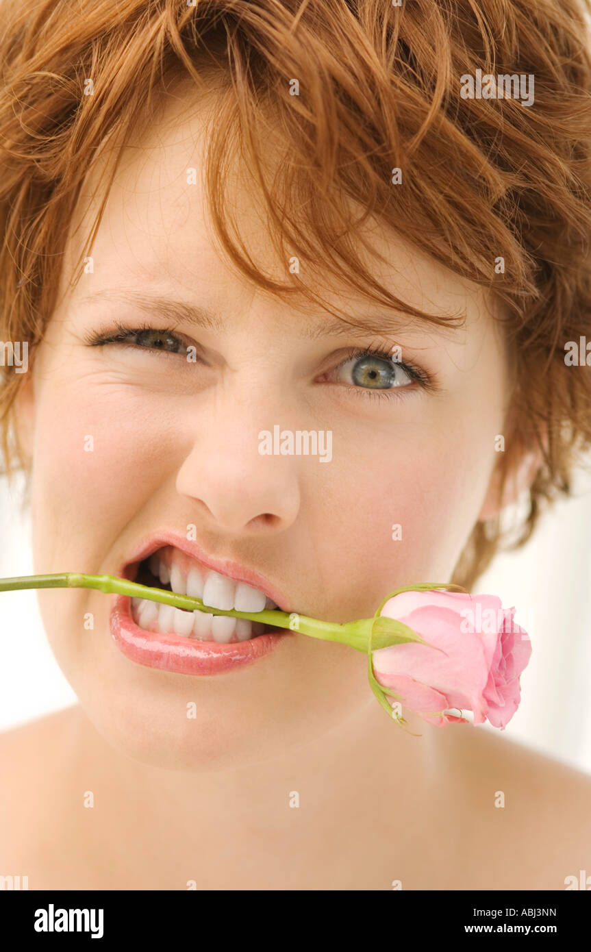 Portrait of young woman with rose between teeth Stock Photo - Alamy