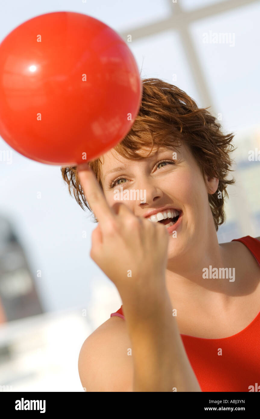 Portrait of young woman balancing red balloon on her finger Stock Photo ...