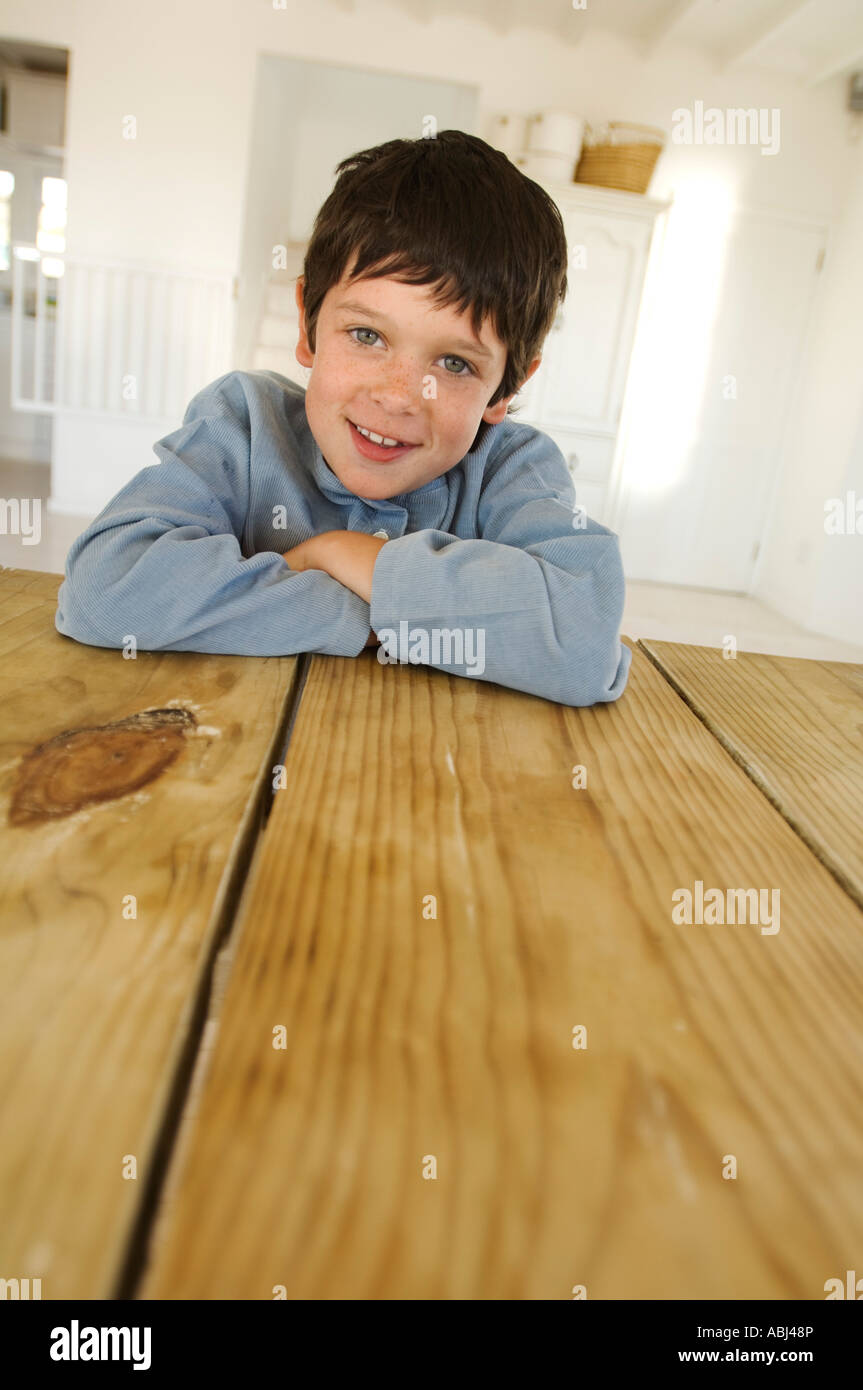 Little boy smiling for the camera, resting on table Stock Photo - Alamy