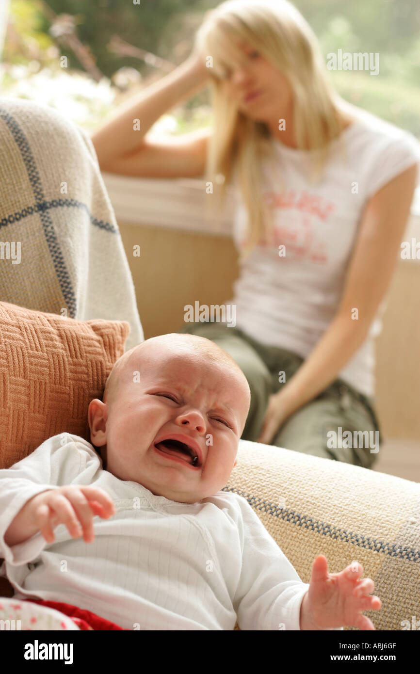 crying baby with stressed teenager in background Stock Photo - Alamy