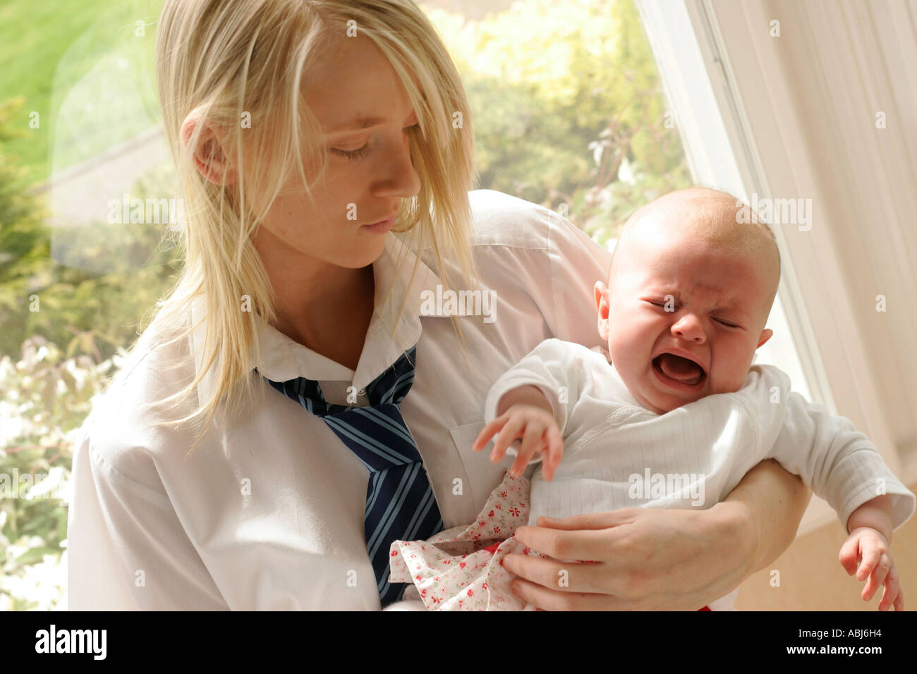 teenager with crying baby looking stressed Stock Photo - Alamy