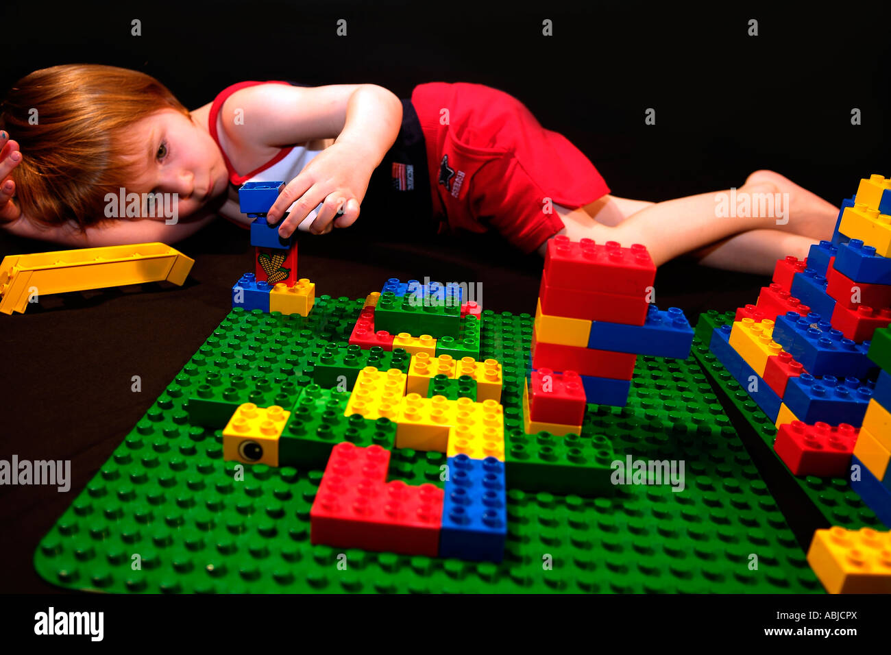 Young blond girl playing Lego toys on a carpet Stock Photo - Alamy