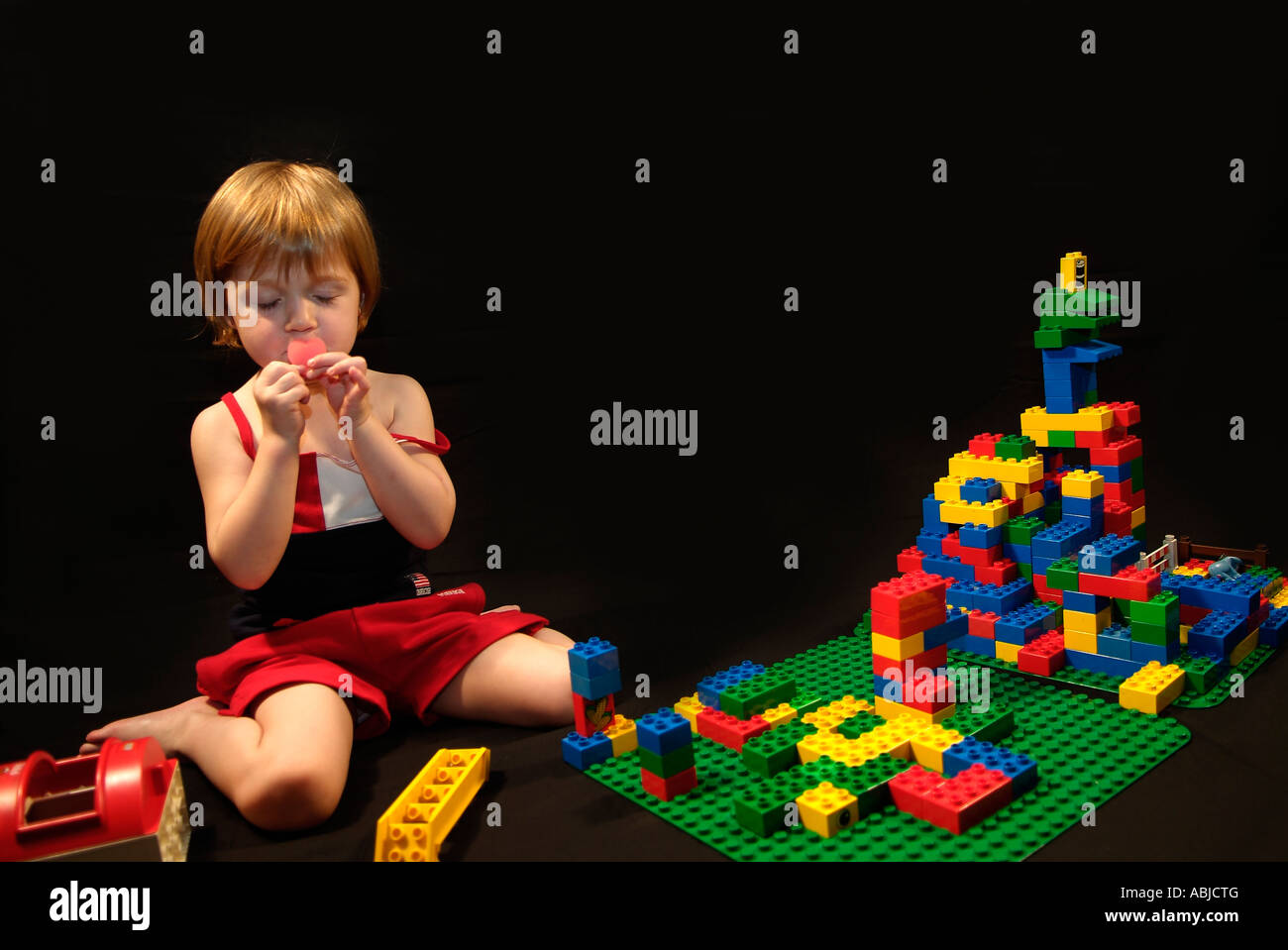 Young blond girl playing Lego toys on a carpet Stock Photo - Alamy