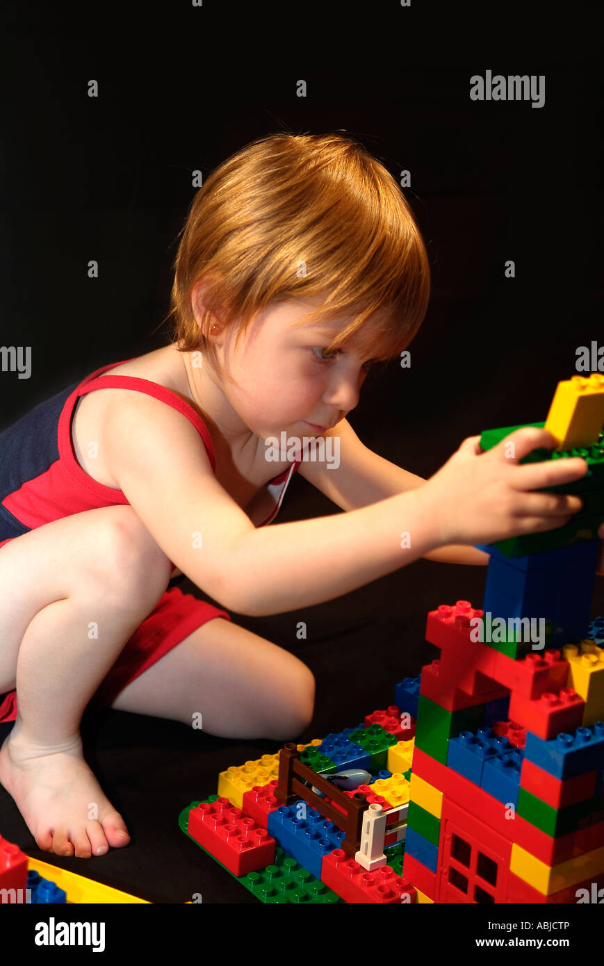 Young blond girl playing Lego toys on a carpet Stock Photo - Alamy