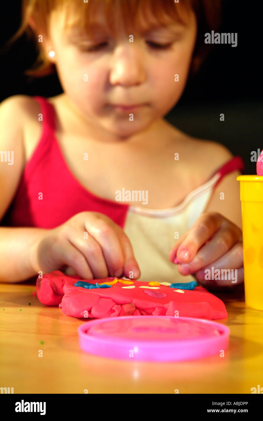 Young girl playing with modeling clay on a table Stock Photo - Alamy