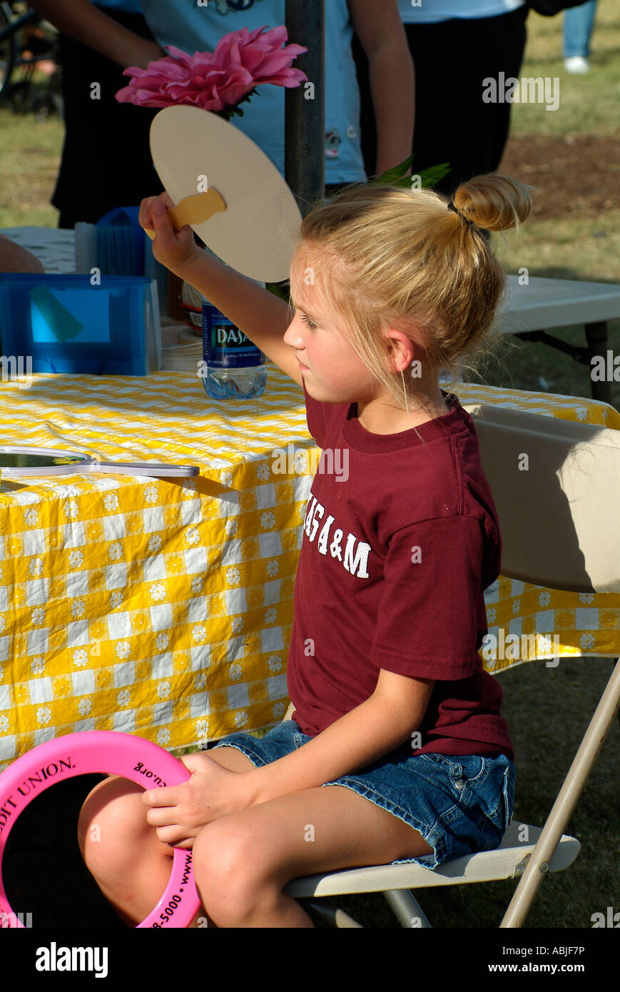 Young girl using a paper fan during a fair in Texas Stock Photo - Alamy
