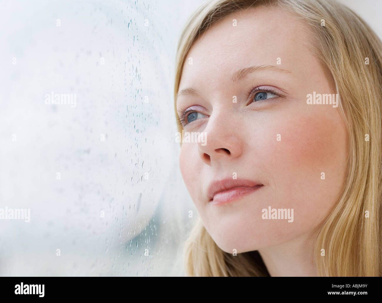 Woman looking out rainy window Stock Photo - Alamy