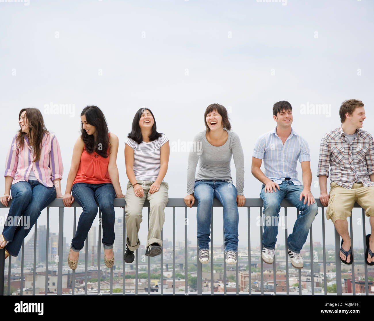 Friends sitting on railing Stock Photo - Alamy