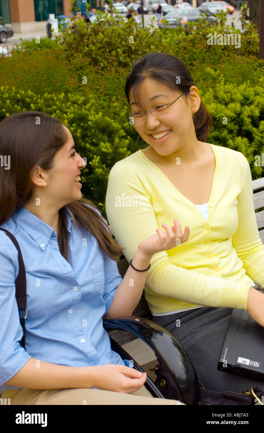 Hispanic American and Korean American girls talking and laughing in ...
