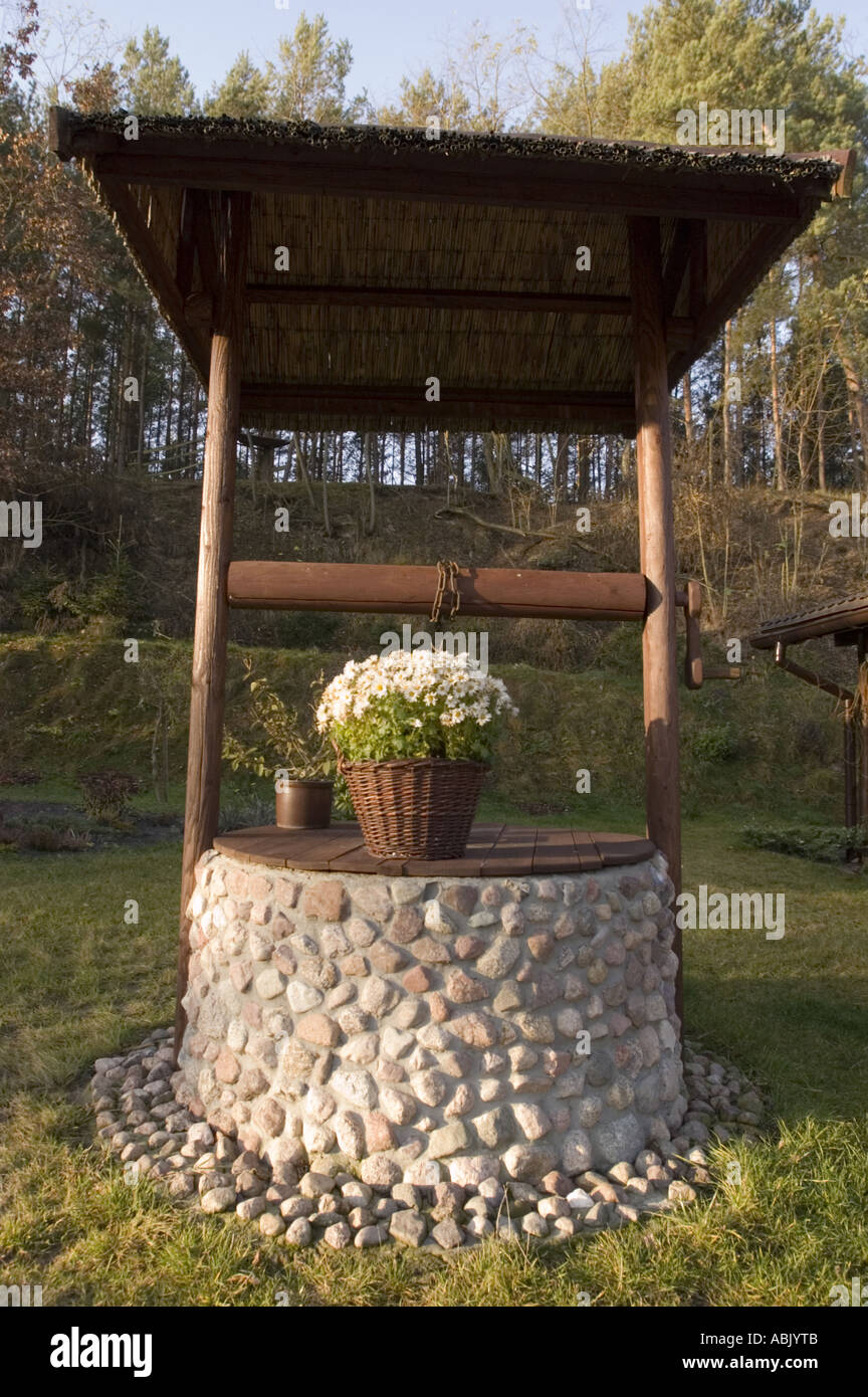 Pot with flowers standing on nice water well in garden Stock Photo - Alamy