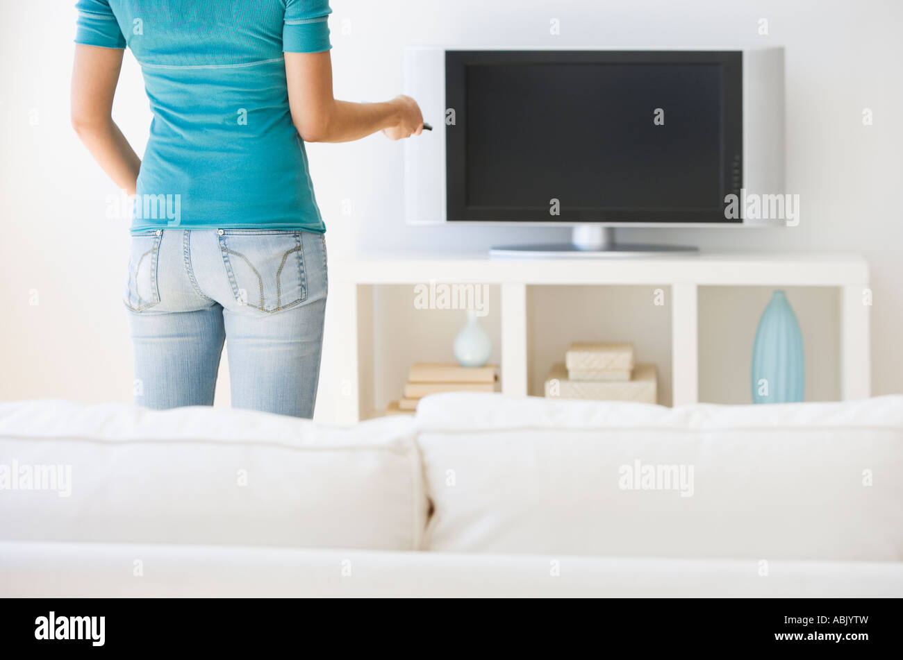 Woman pointing remote control at television Stock Photo - Alamy