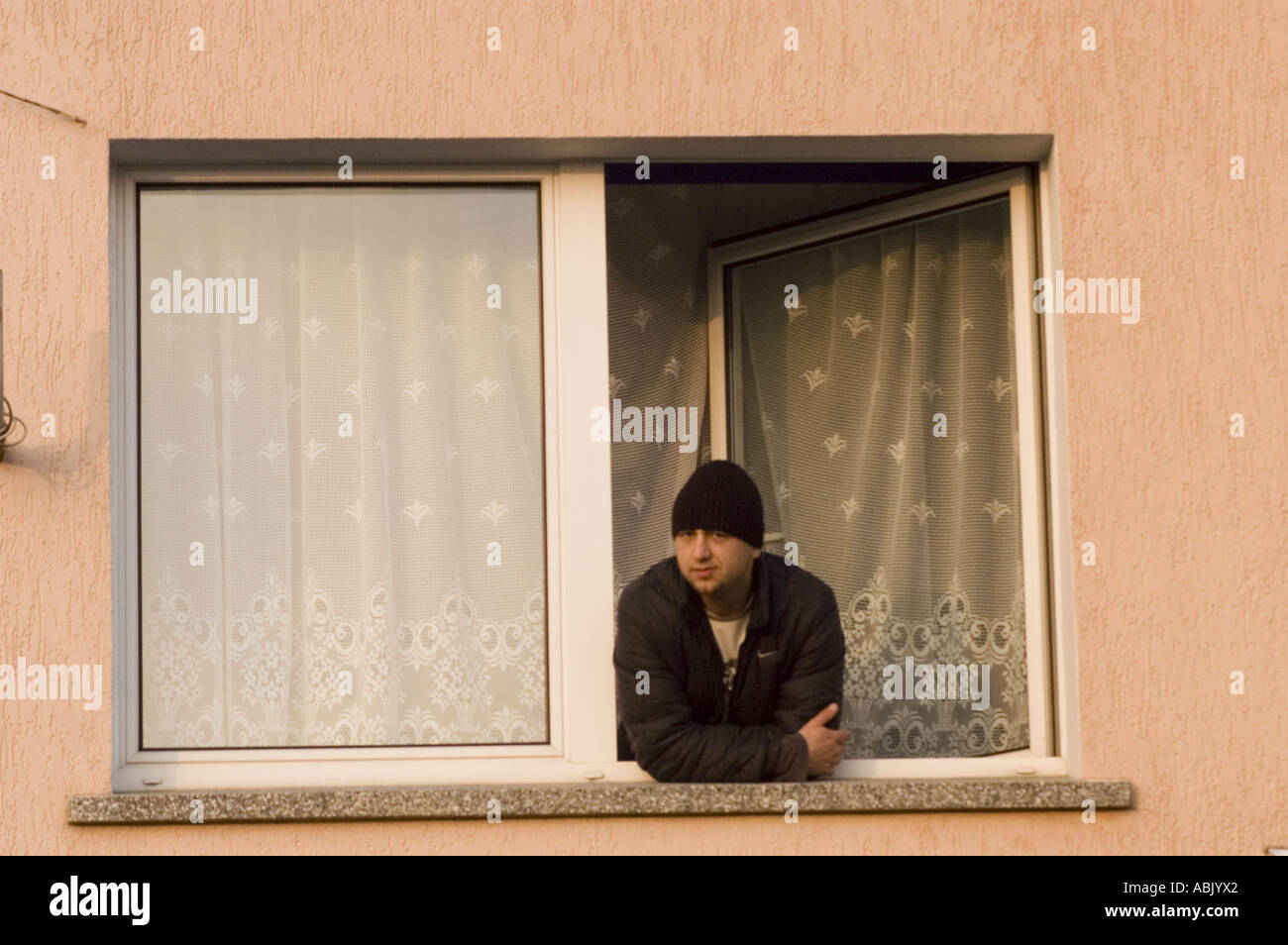 Young man with cap looking through window of his house Stock Photo - Alamy