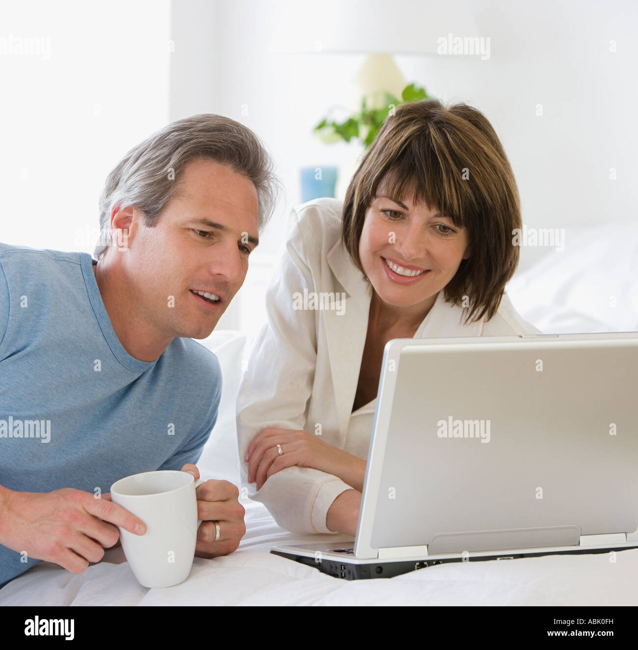 Couple looking at laptop on bed Stock Photo - Alamy