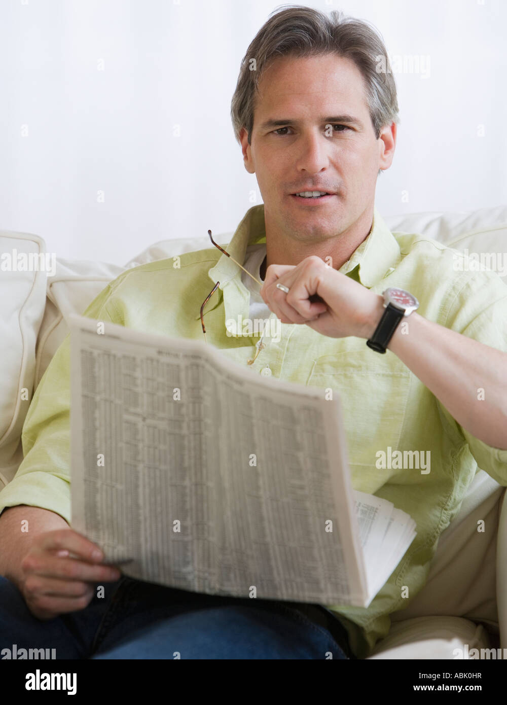 Man holding newspaper on sofa Stock Photo - Alamy