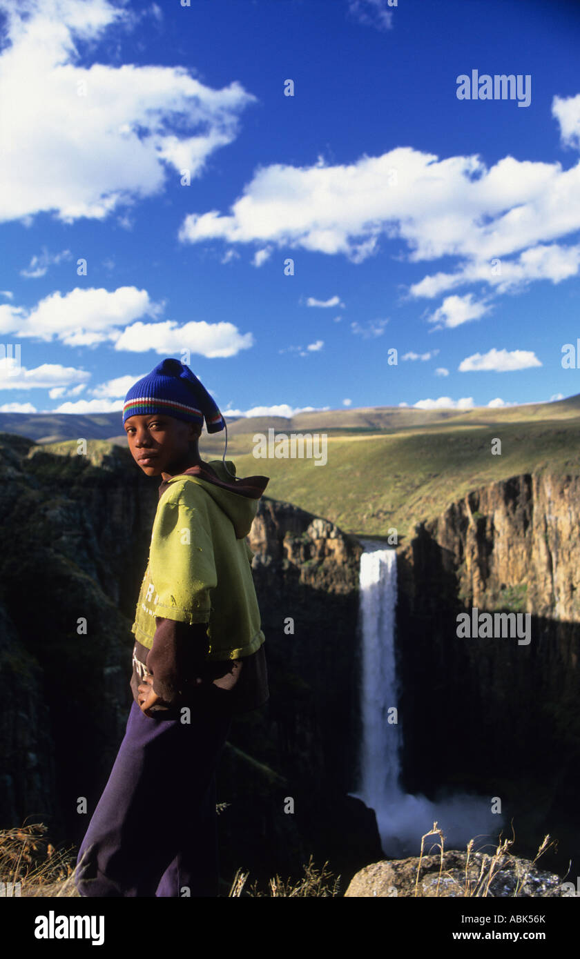 A young African boy stands in front of Maletsunyane waterfall ...