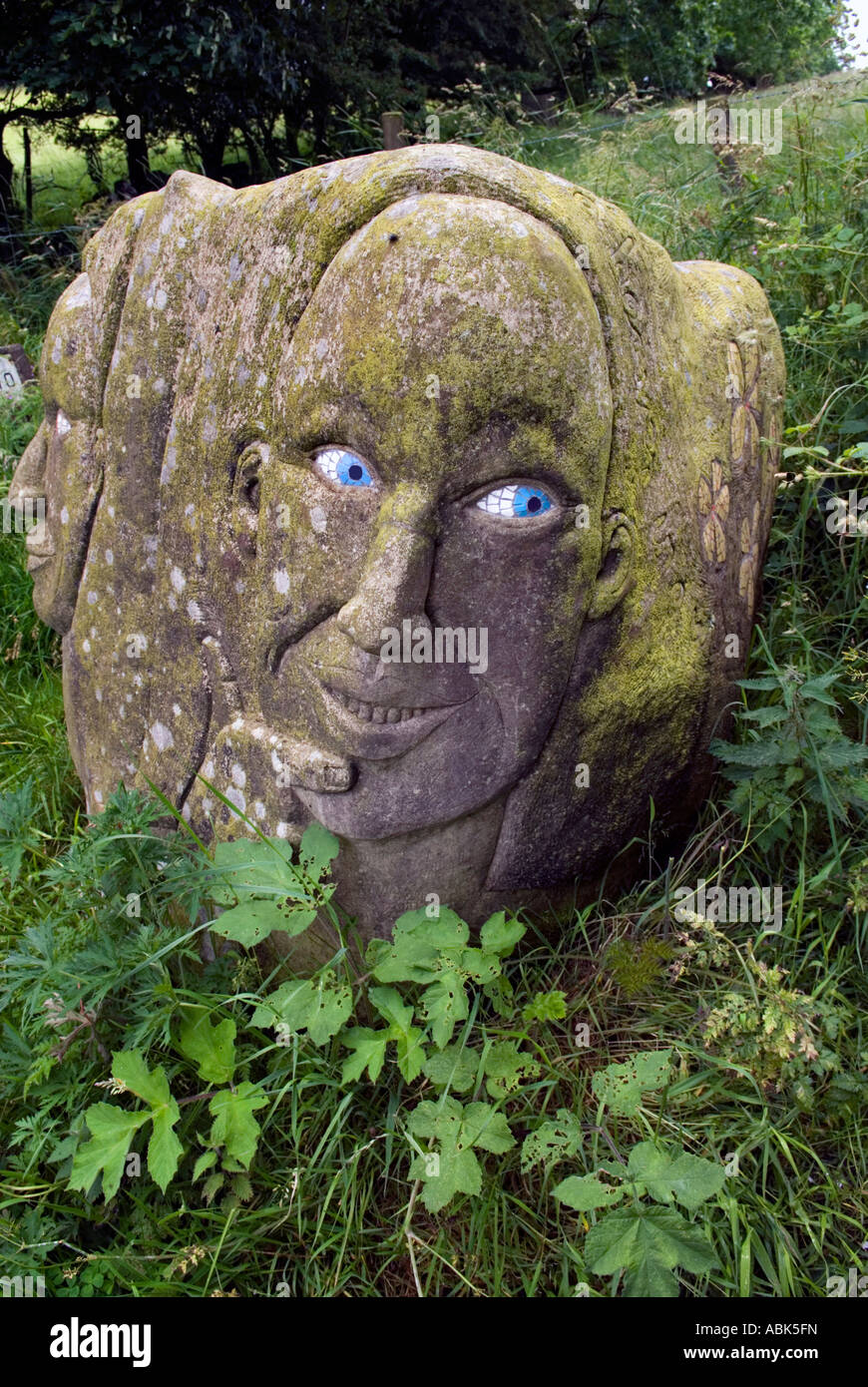 Two stone heads carved into a rock by the side of a country lane near ...