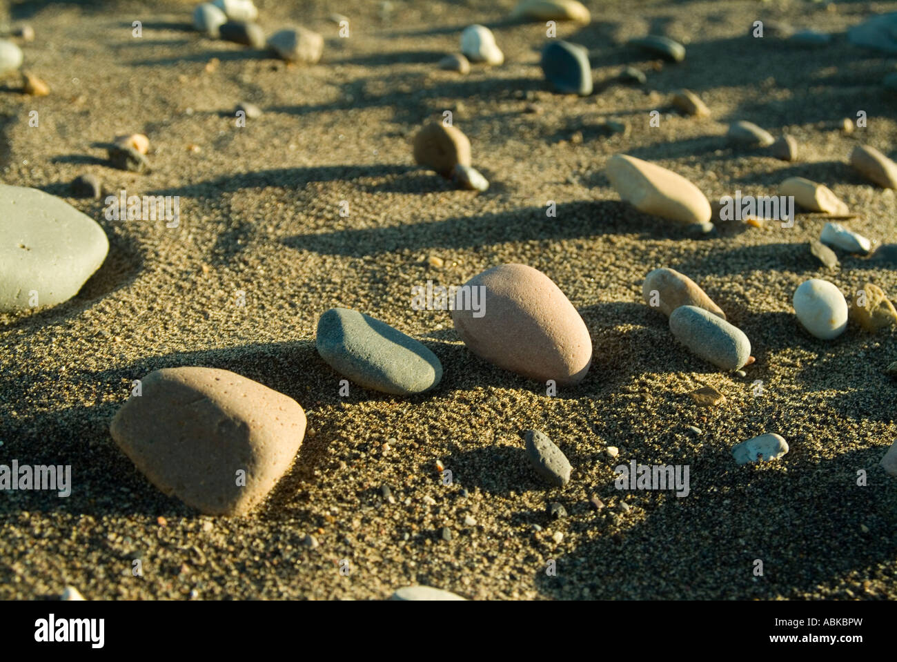 Pebbles on a beach lit by a low sun in winter at Spurn Point East ...