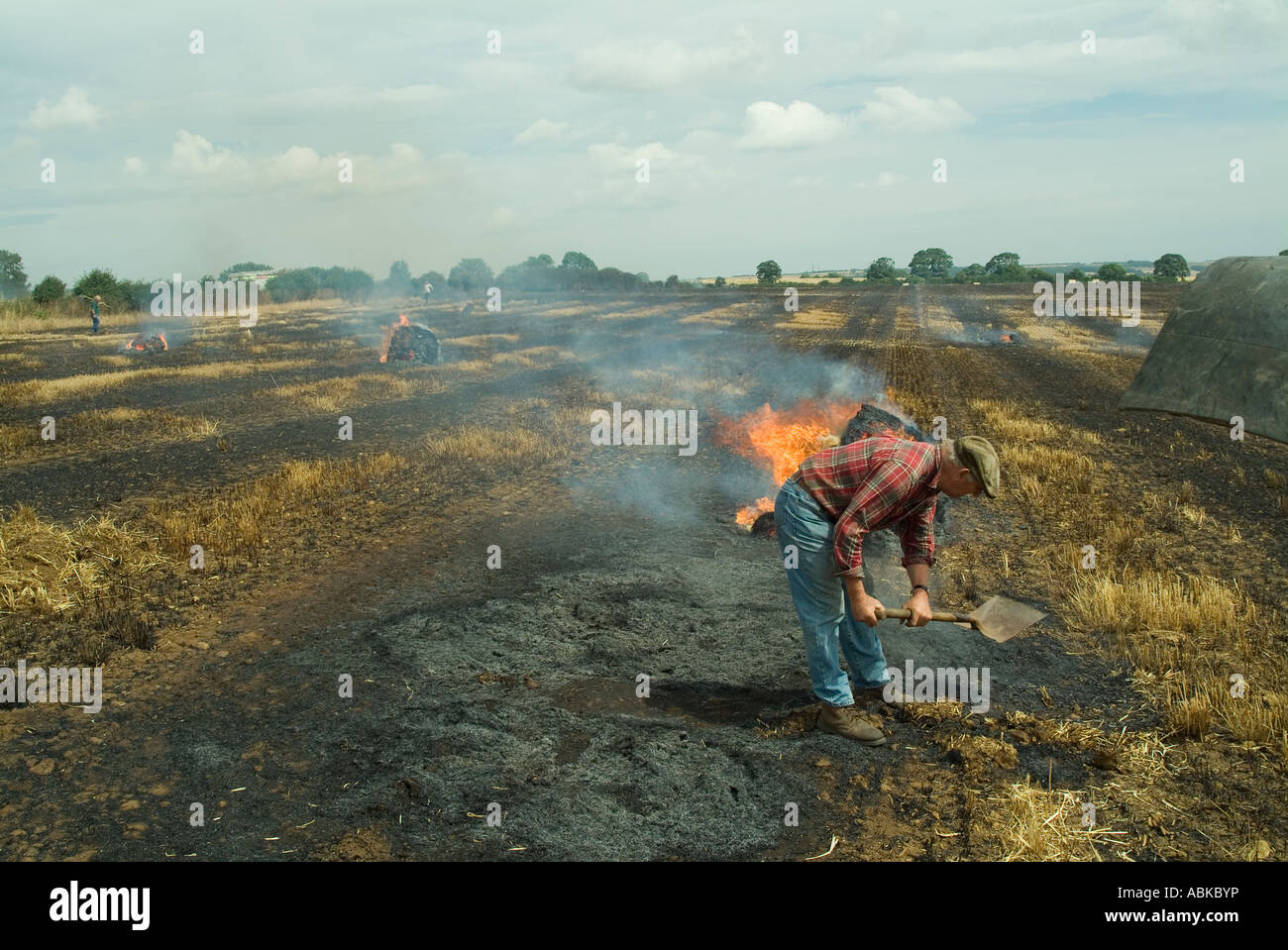 Farmer extinguishing burning barley field after the baler fire ...