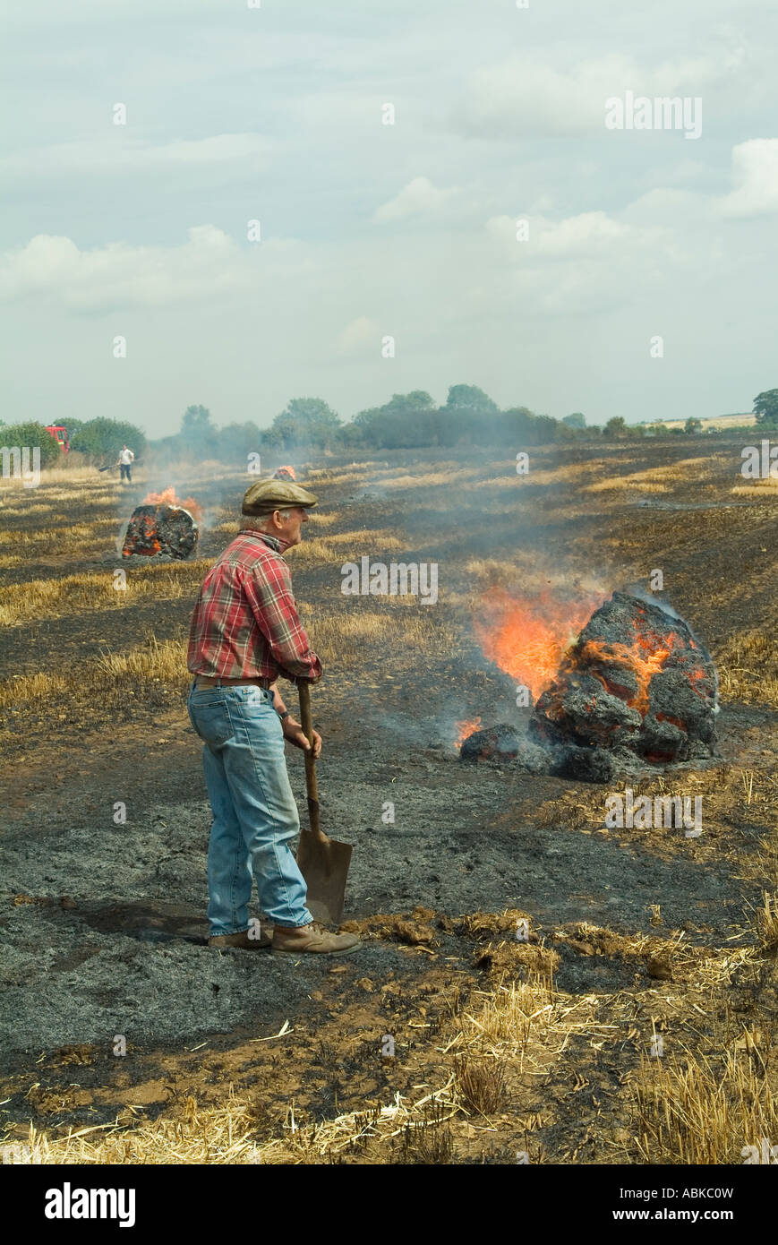 Farmer extinguishing burning barley field after the baler fire ...