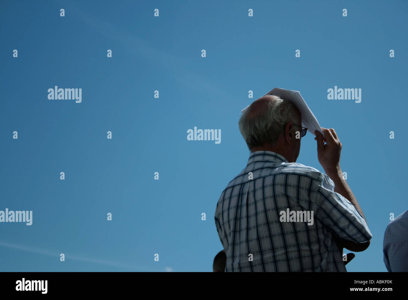 Man covering bald head from sun with paper Stock Photo - Alamy