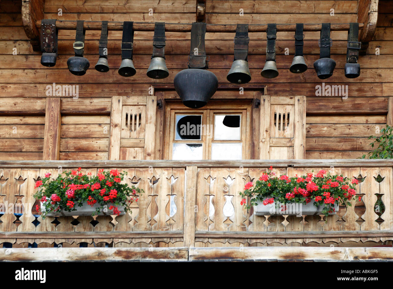 Traditional wooden chalet with cow bells and geraniums in Alpine ...