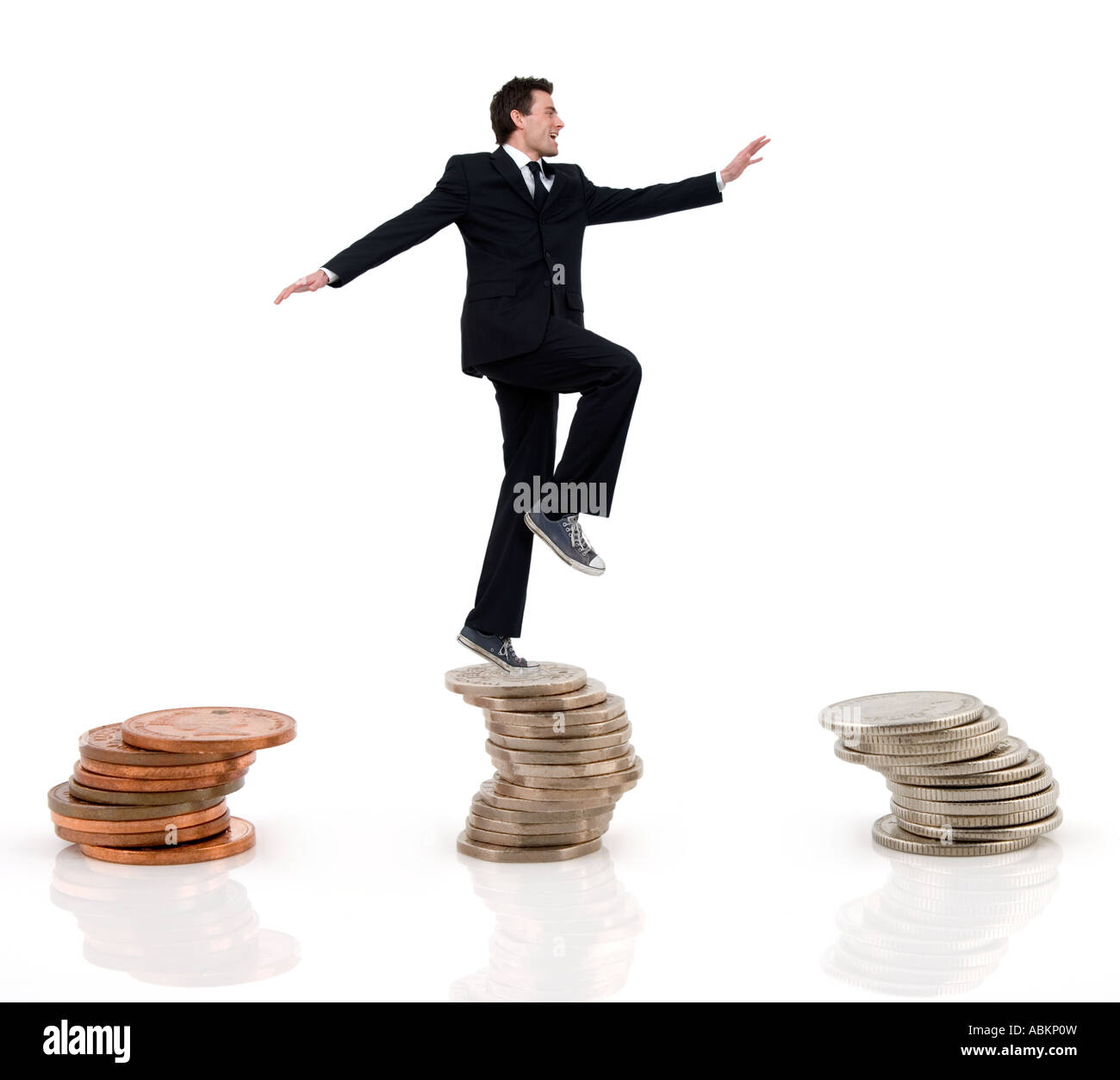 man jumping across piles of coins balancing your money Stock Photo - Alamy